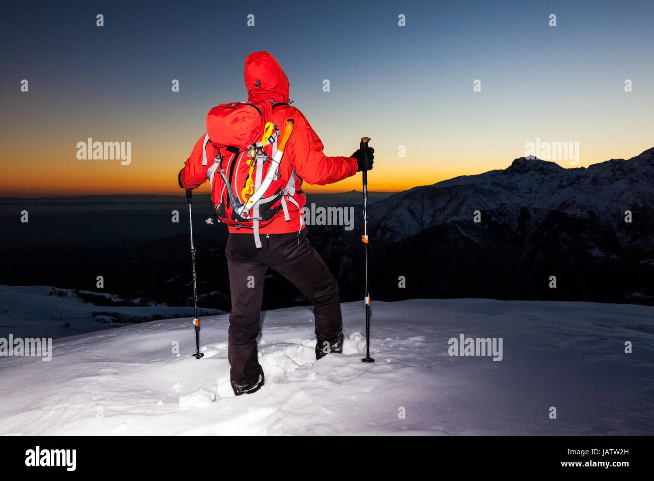 Winter hiking: man stands on a snowy ridge looking at the sunset (point ...