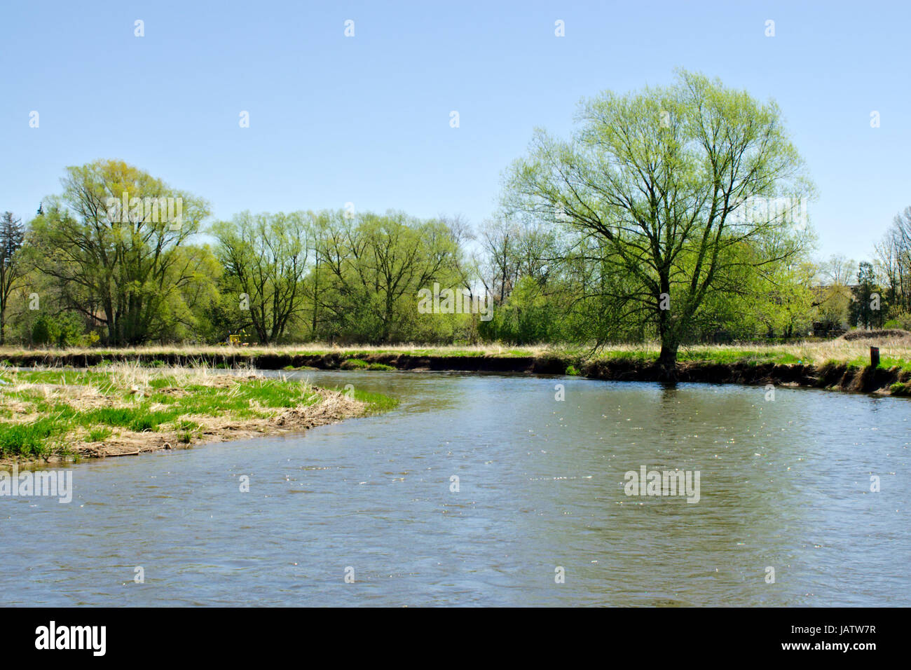 Wide river curving left by trees in spring on blue sky Stock Photo - Alamy