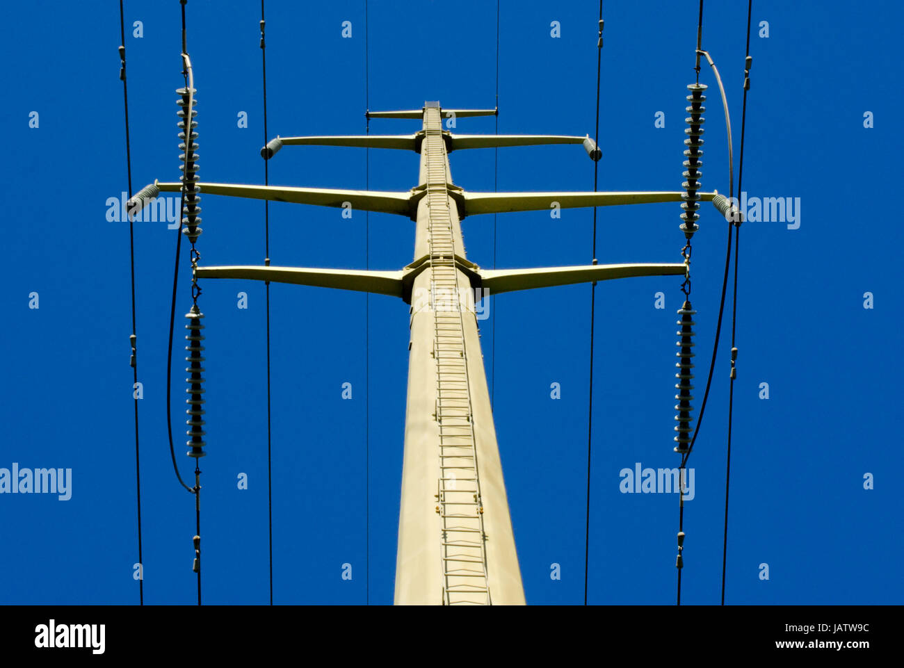 Looking up concrete electrical tower with cables and insulators against ...