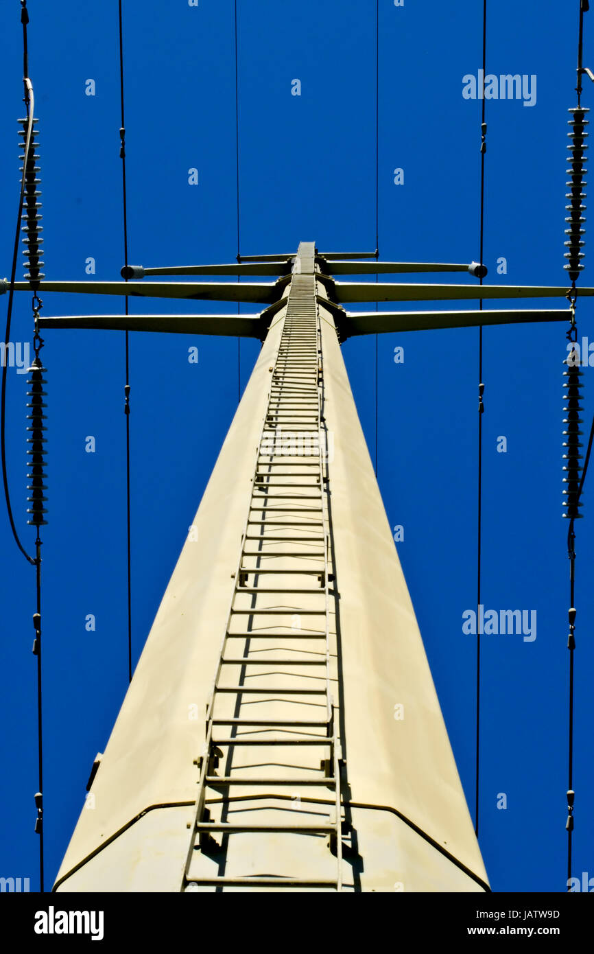 Looking up ladder on electrical tower with cables and insulators ...