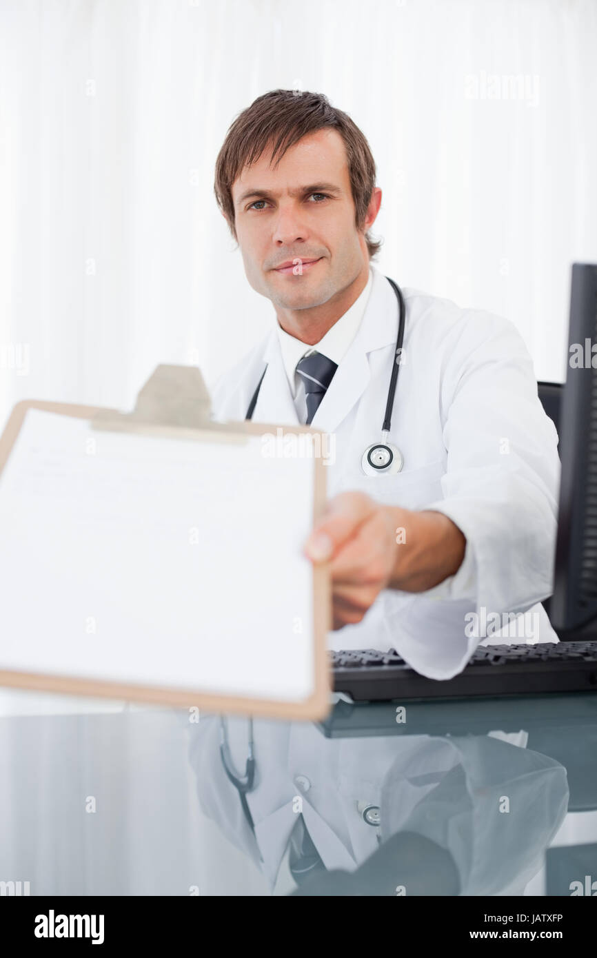 Doctor holding a clipboard while sitting at the desk Stock Photo - Alamy