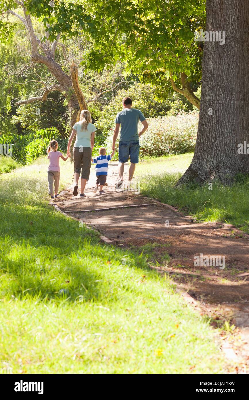 Two kids holding their parents hands as they walk Stock Photo - Alamy