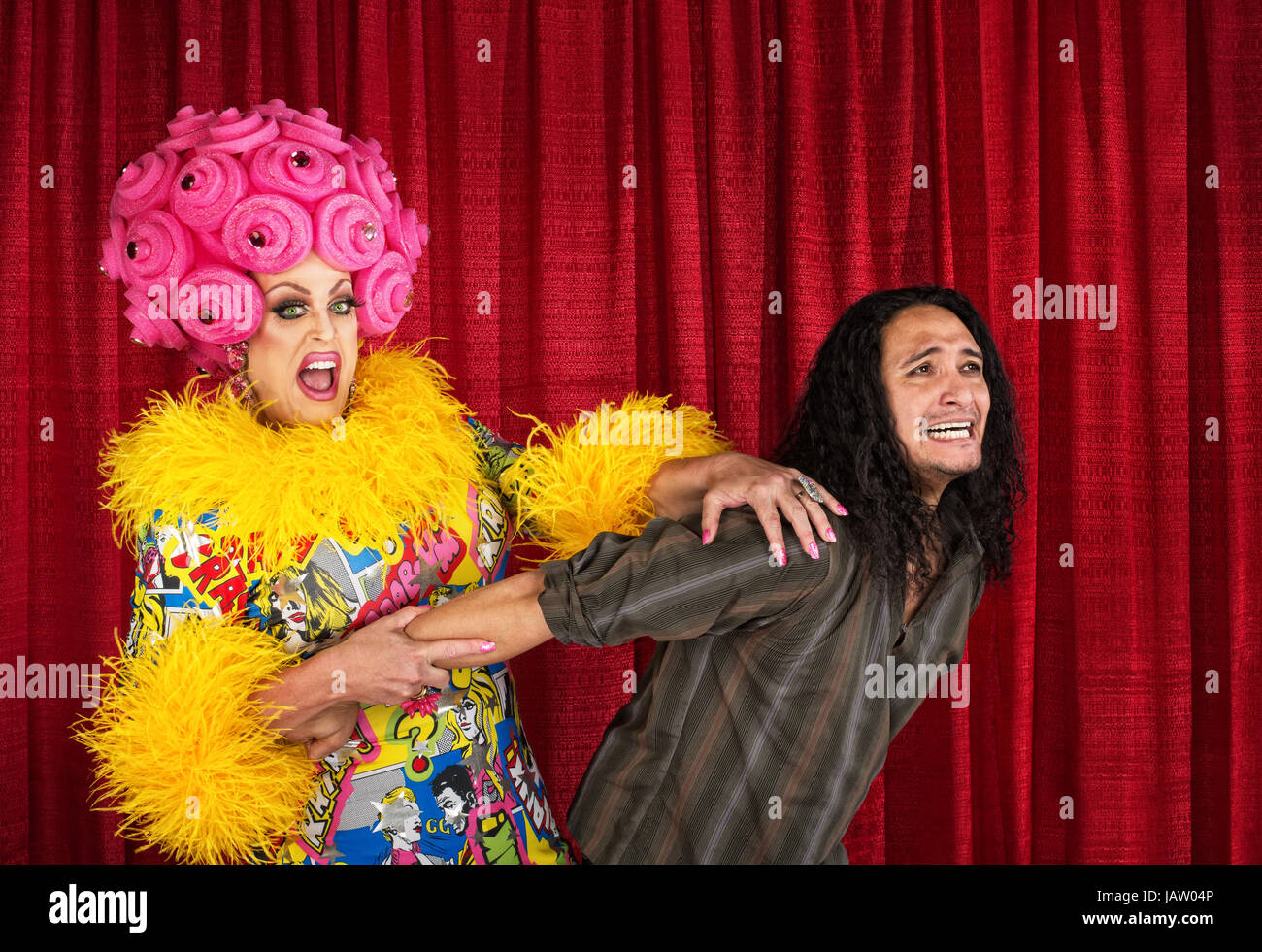 Excited cross-dressing queen pulling on scared man Stock Photo - Alamy