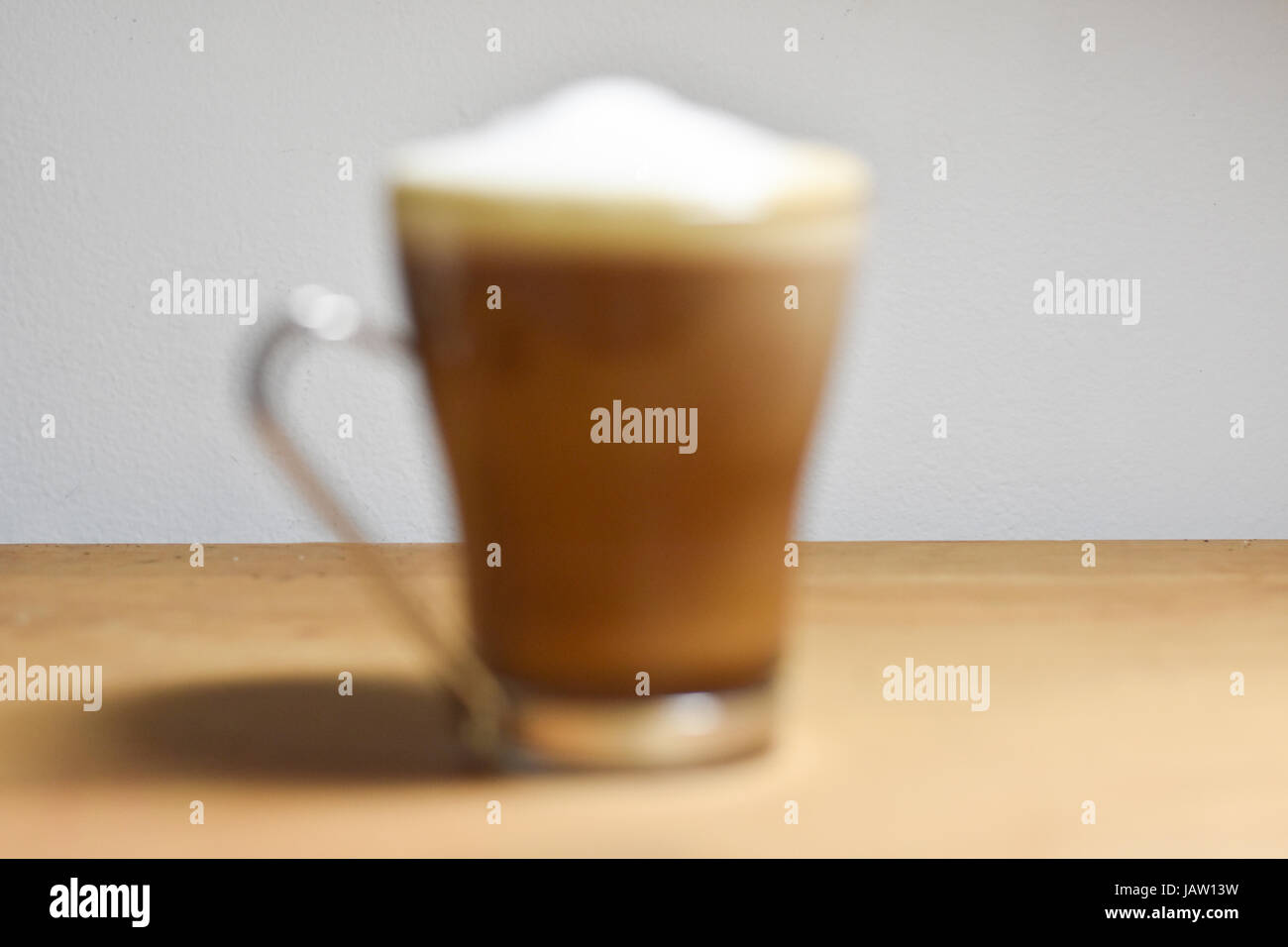 Frothy cream atop a cappuchino in an Italian glass cup with stainless ...