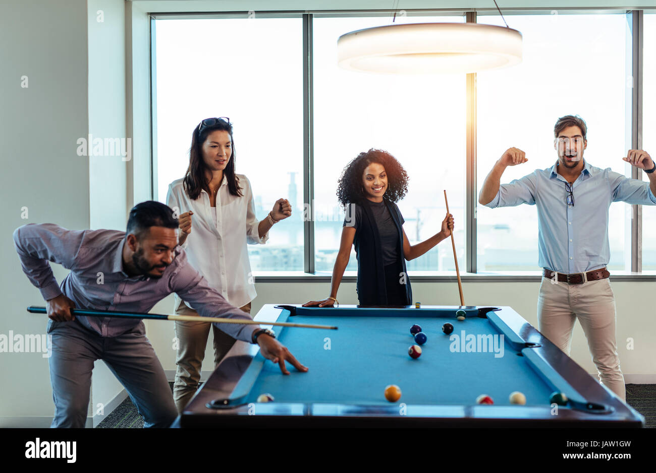 Young men and woman playing billiards at office after work. business ...