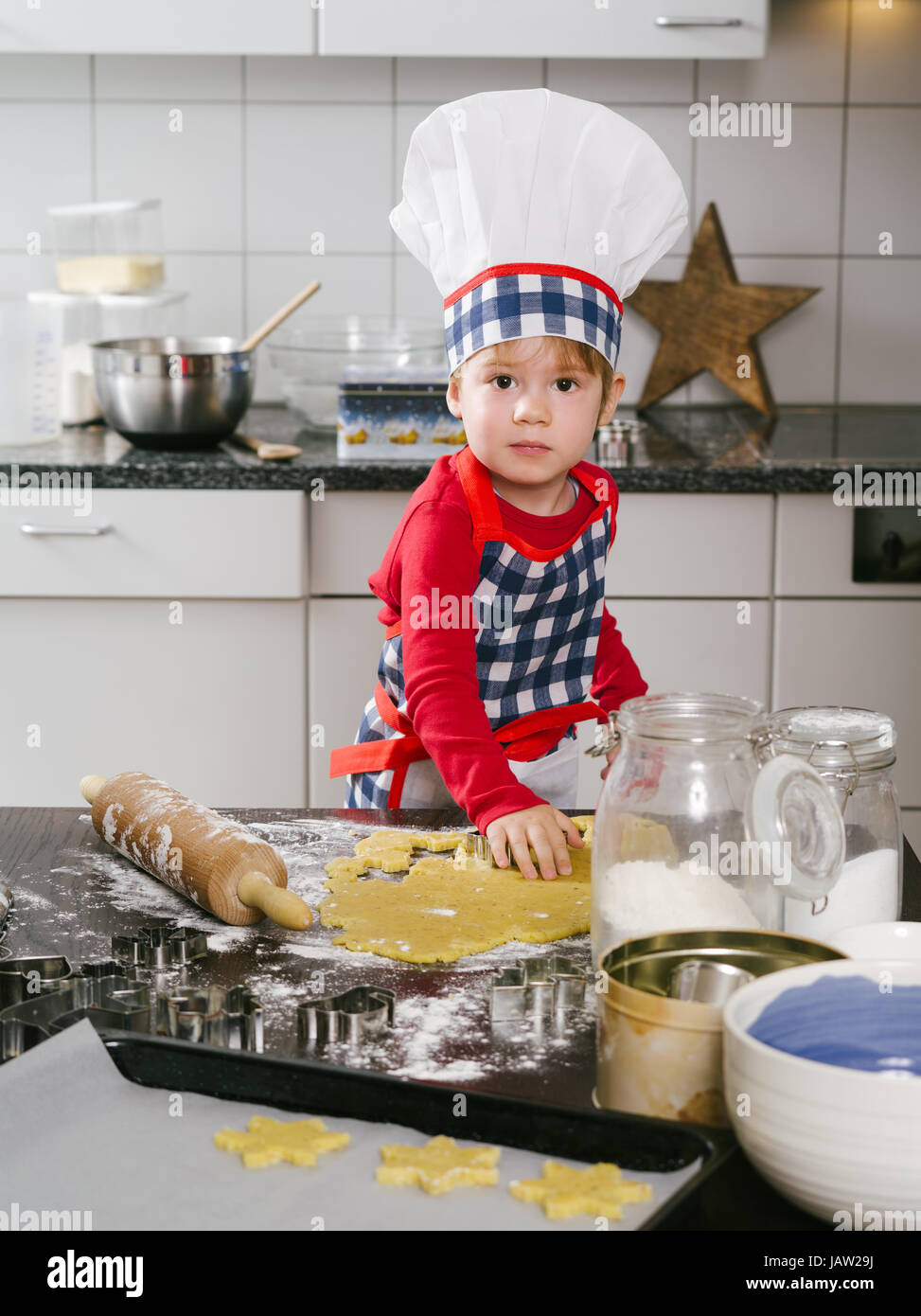Photo of an adorable boy in a chef hat and apron making snowflake ...