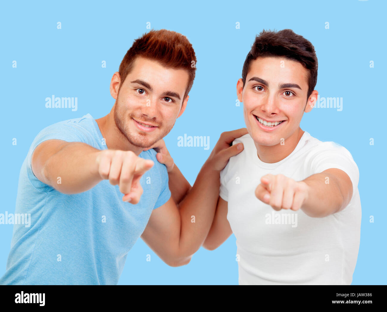 Couple of best friends pointing to the camera on a blue background ...