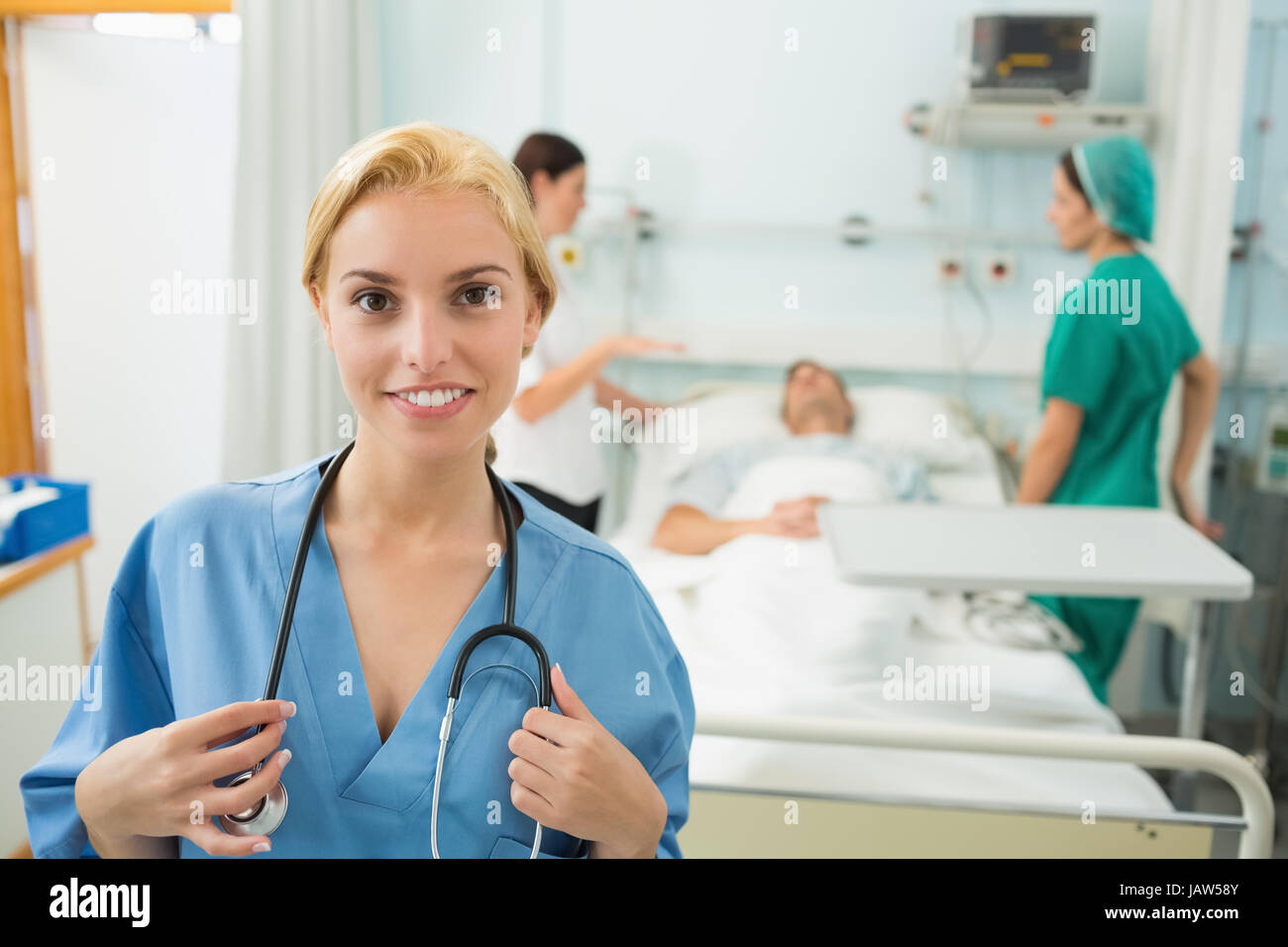 Blonde nurse looking at camera while smiling in hospital ward Stock ...
