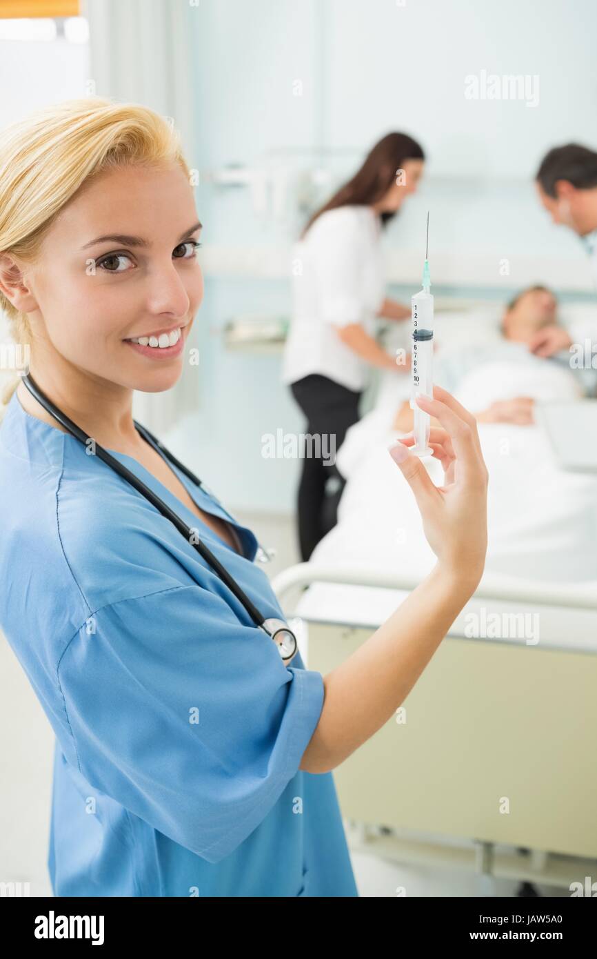 Nurse looking at camera while holding a syringe Stock Photo - Alamy