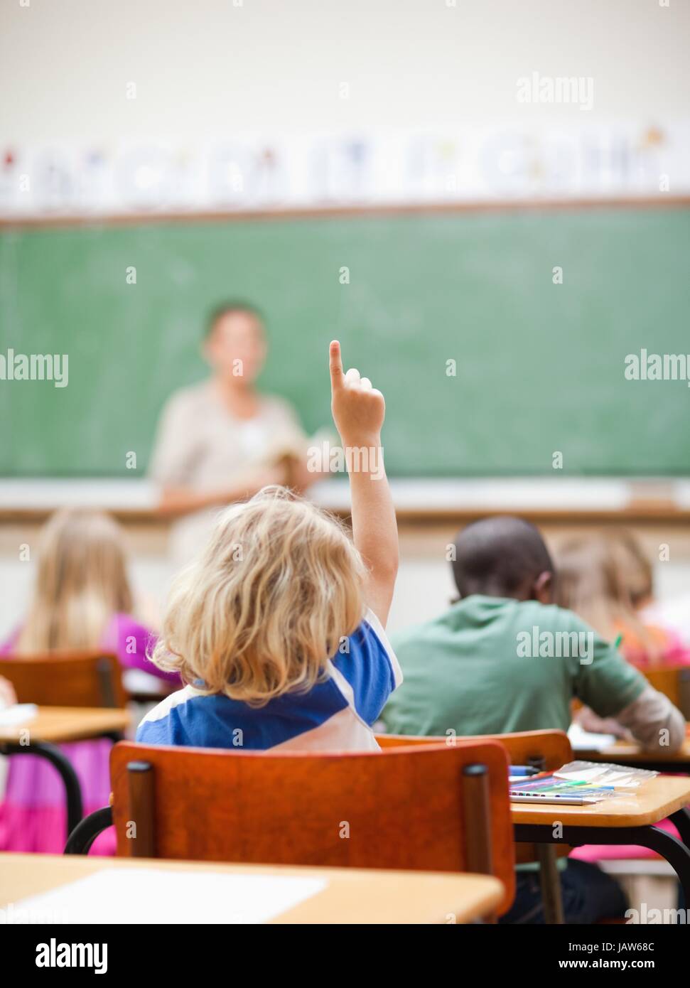 Boy raising his hand during lesson Stock Photo - Alamy