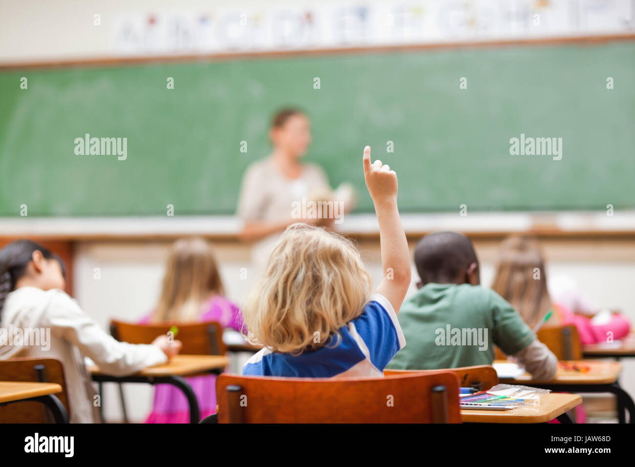 Little boy raising his finger during lesson Stock Photo - Alamy