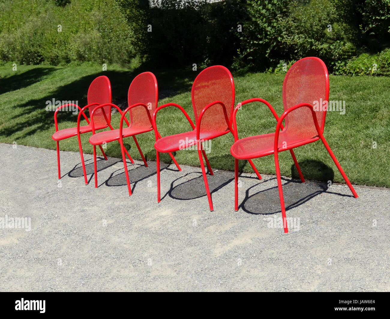 Four empty red metal chairs in a row Stock Photo - Alamy