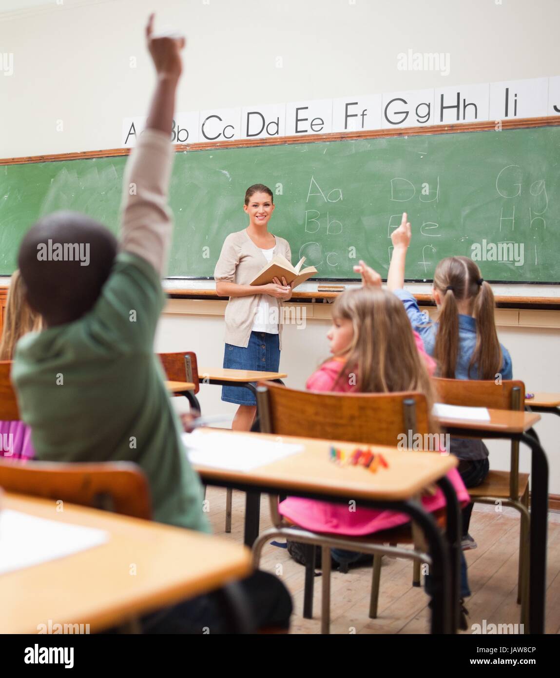 Back view of young pupils raising hands Stock Photo - Alamy