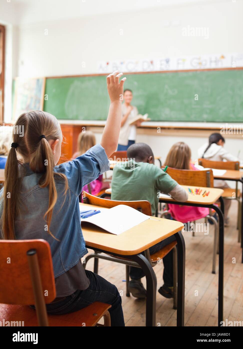 Back view of elementary school student raising hand during lesson Stock ...