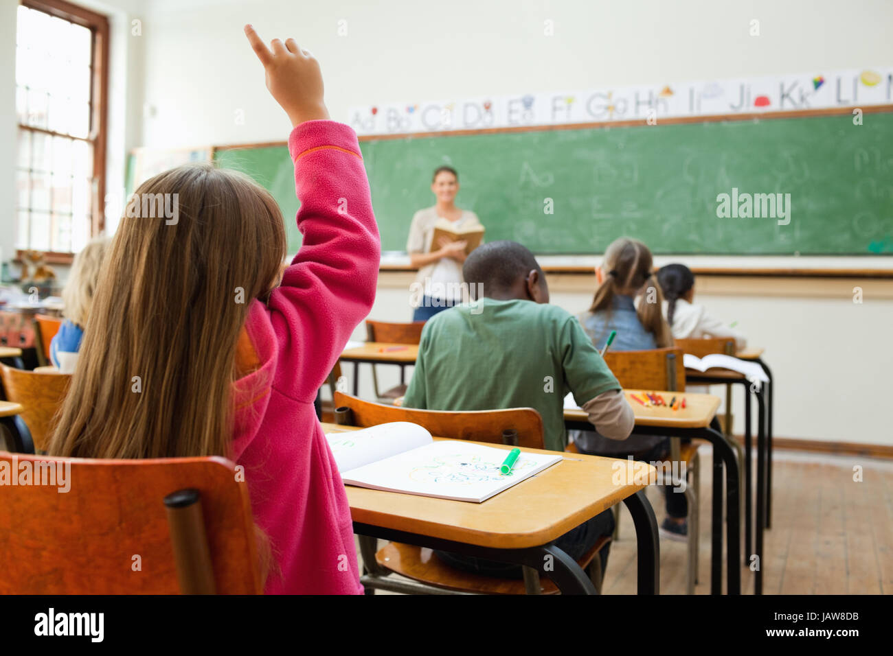 Back view of little girl raising hand during lesson Stock Photo - Alamy