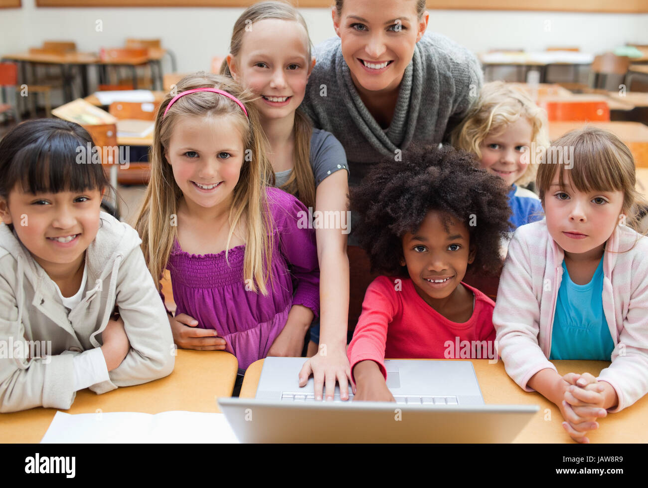 Smiling elementary teacher with students and laptop Stock Photo - Alamy