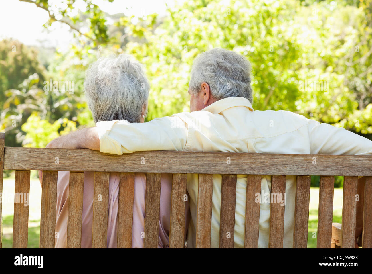 Man sitting on a bench with his arm around his friend Stock Photo - Alamy