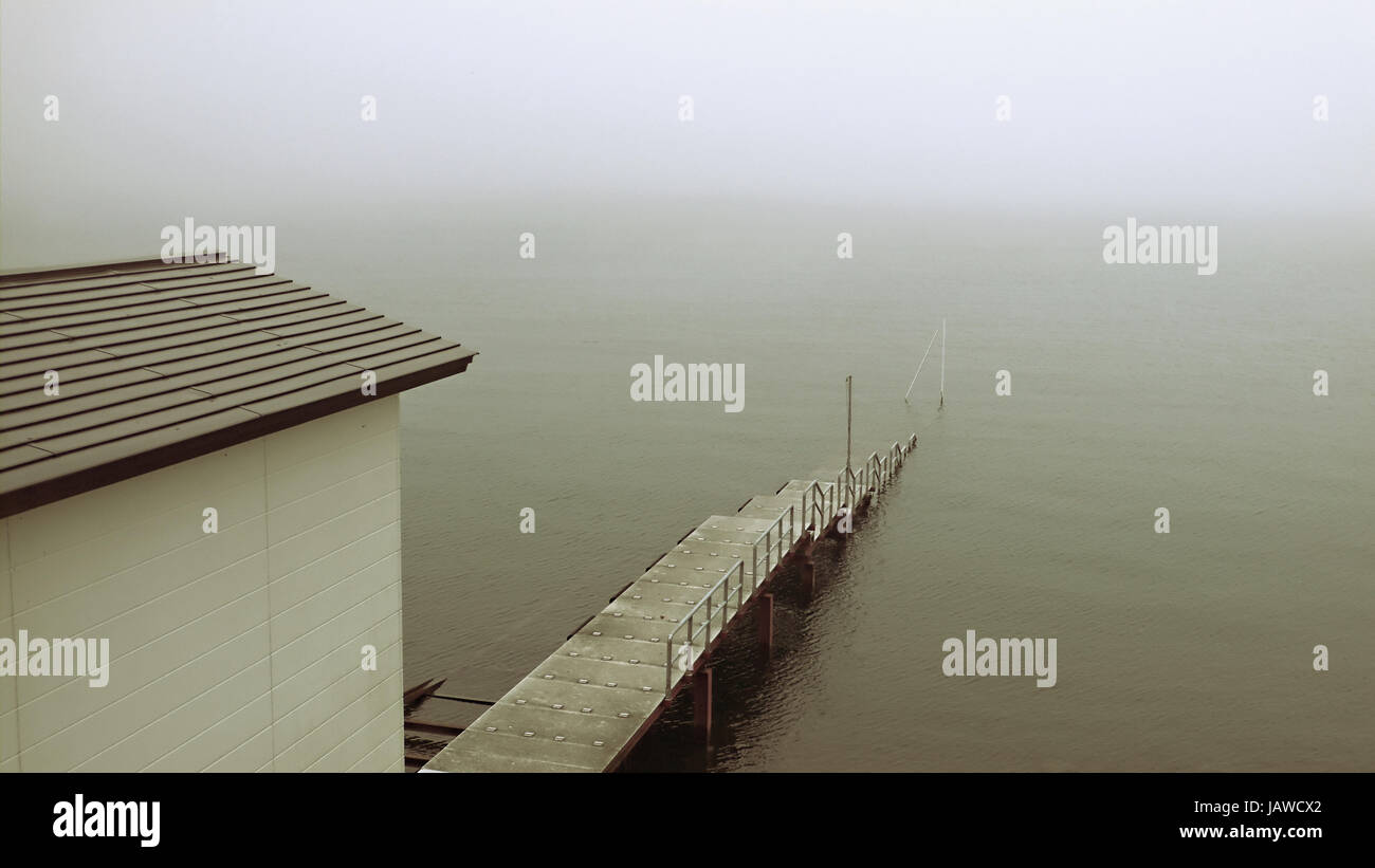 old sinking pier and building on the misty lake shore Stock Photo - Alamy