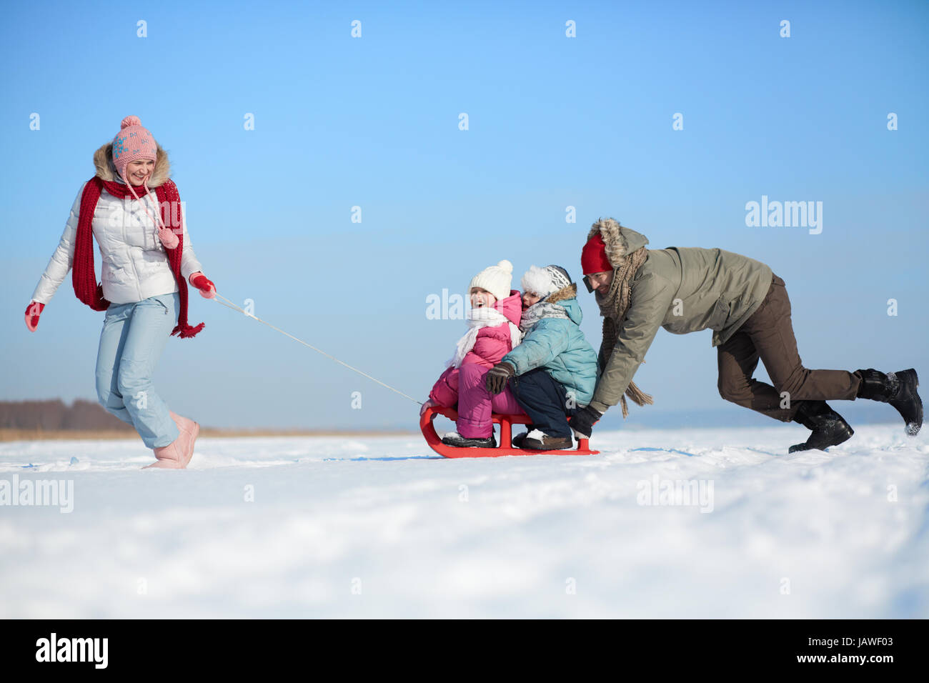 Happy kids enjoying riding on sledge with their parents Stock Photo - Alamy