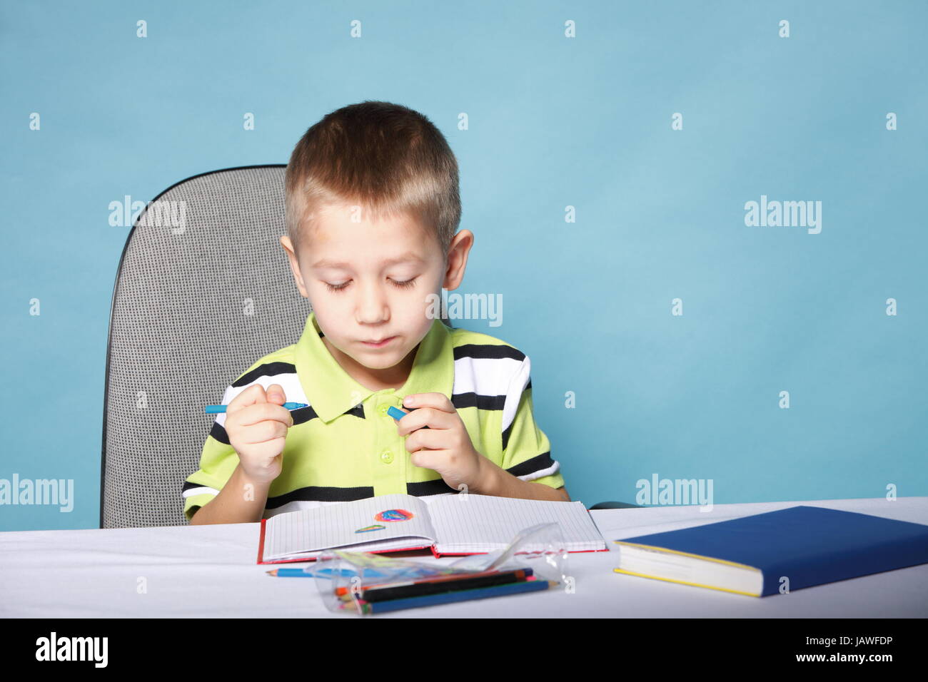 little boy drawing with color pencils on blue background Stock Photo ...