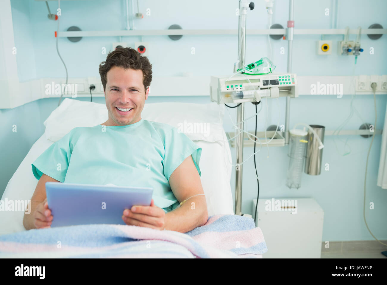 Male patient holding a tactile tablet while lying on a bed in a ...