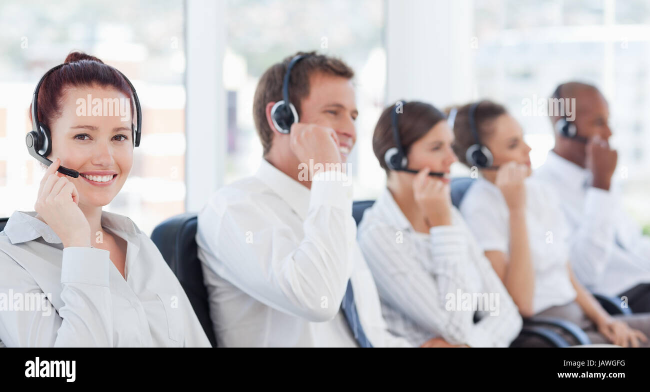 Smiling call center agent sitting next to her colleagues Stock Photo ...