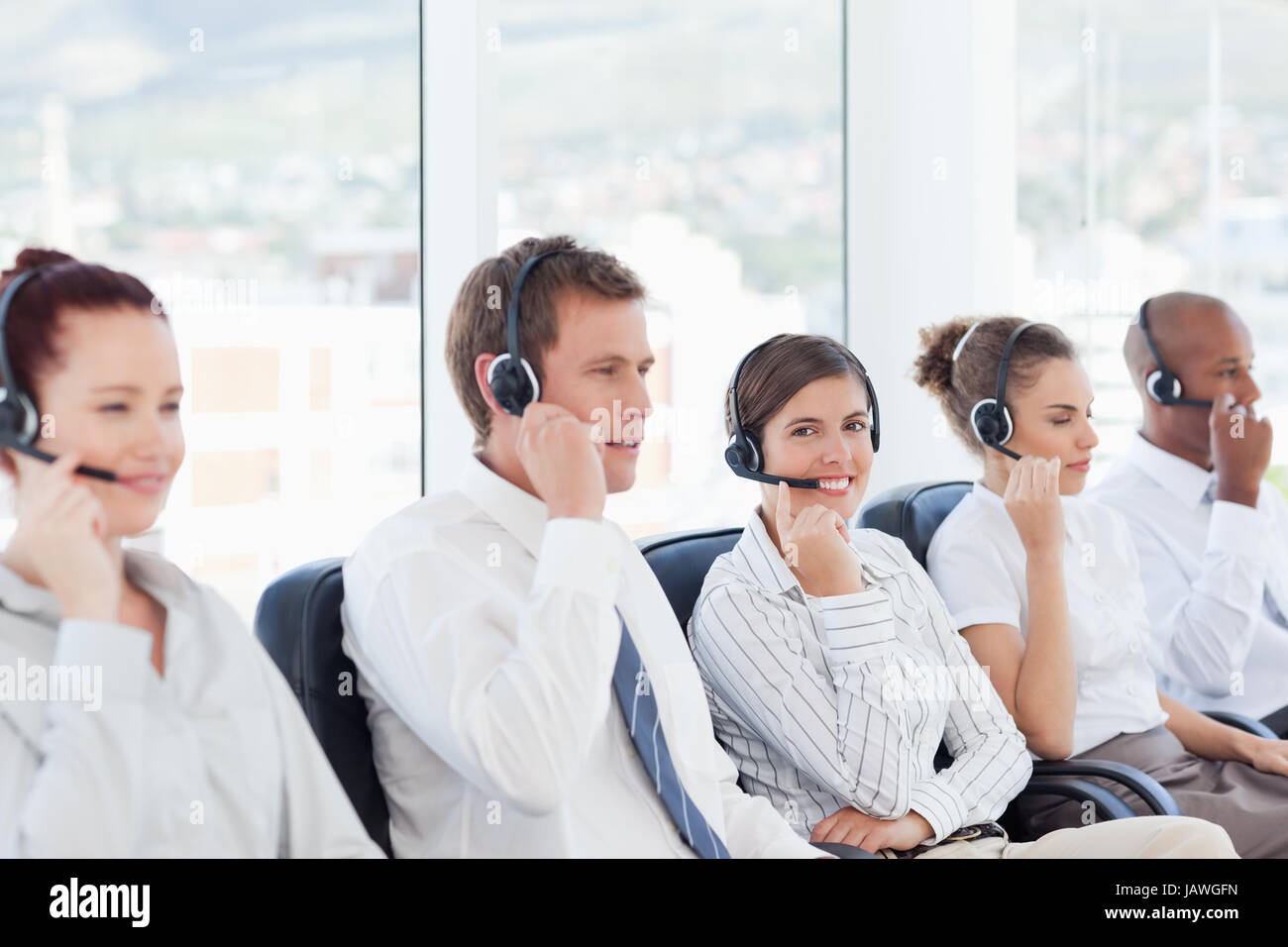 Smiling call center agent sitting among her colleagues Stock Photo - Alamy