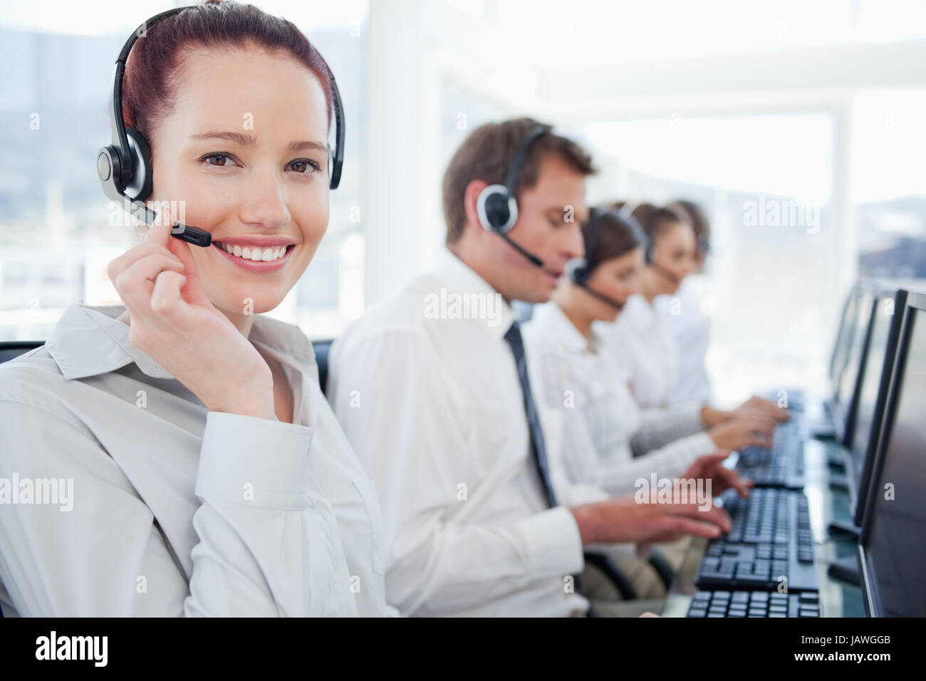 Smiling call center agent with her colleagues behind her Stock Photo ...