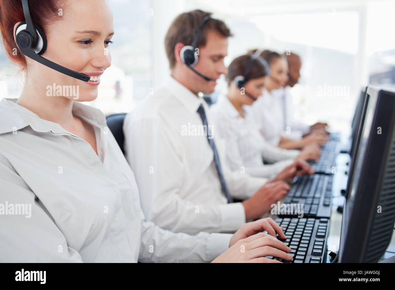 Call center agents sitting in a line at work Stock Photo - Alamy