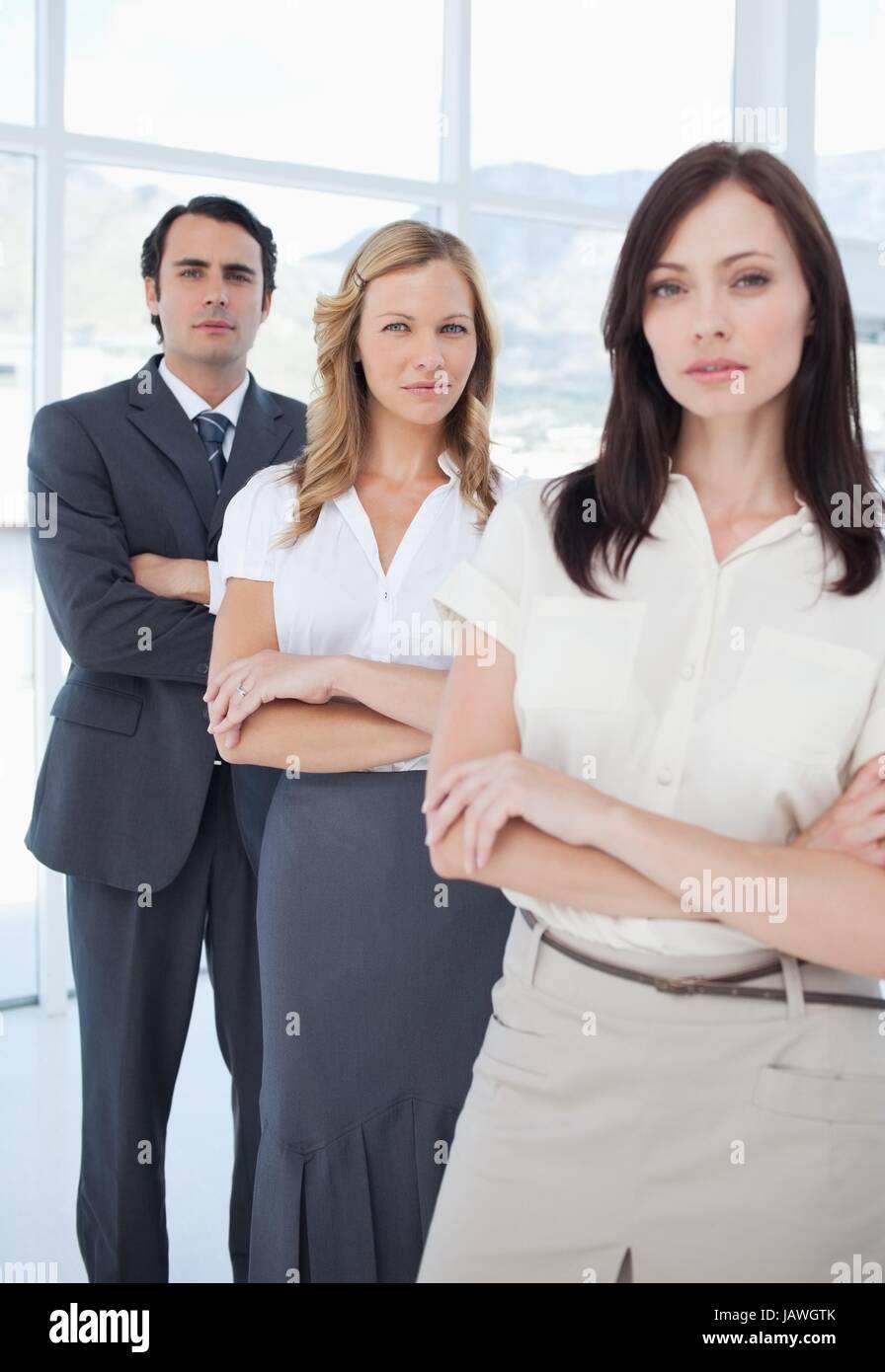 Three serious work colleagues standing behind each other with their ...
