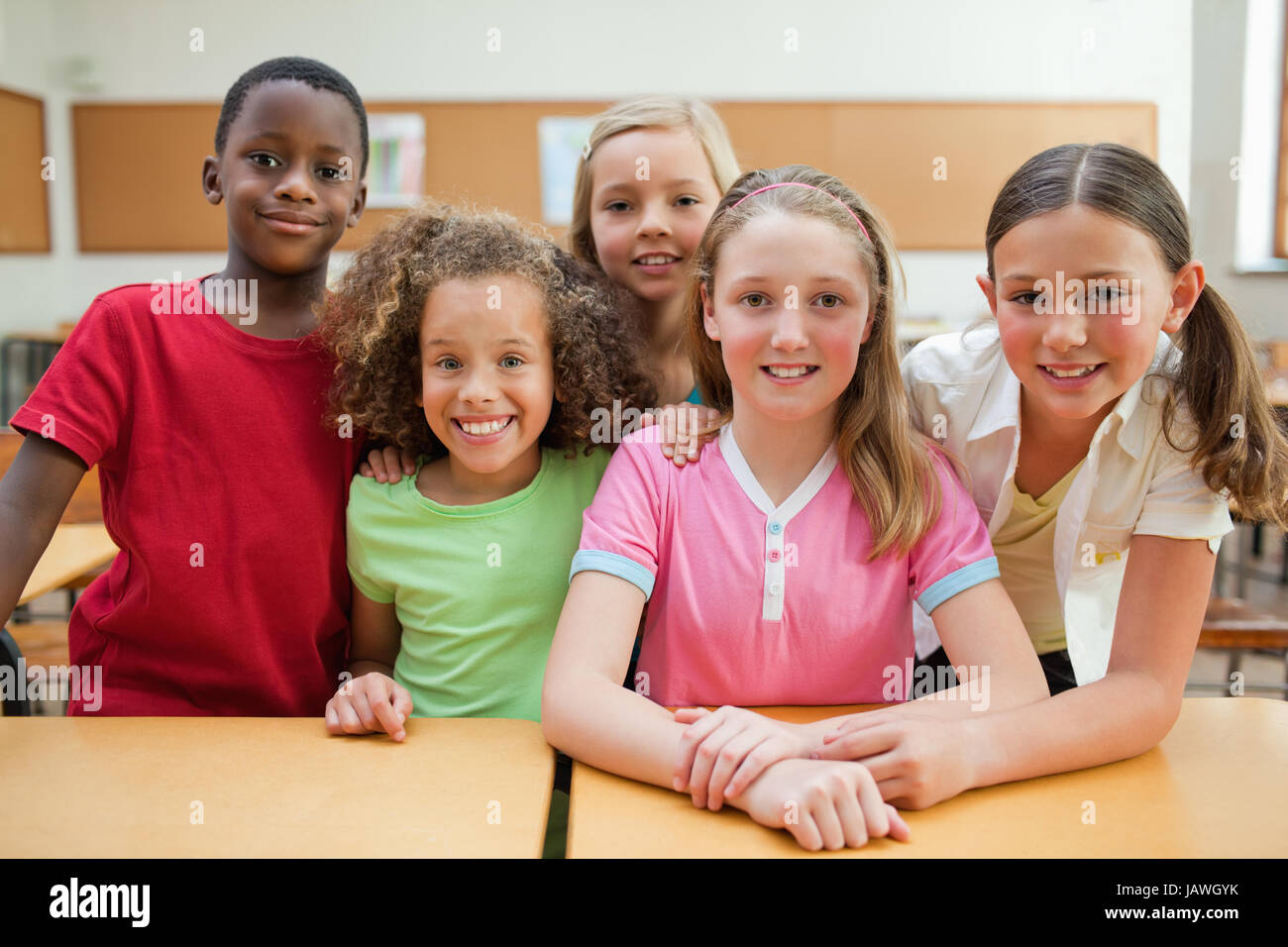 Smiling students together behind desk Stock Photo - Alamy