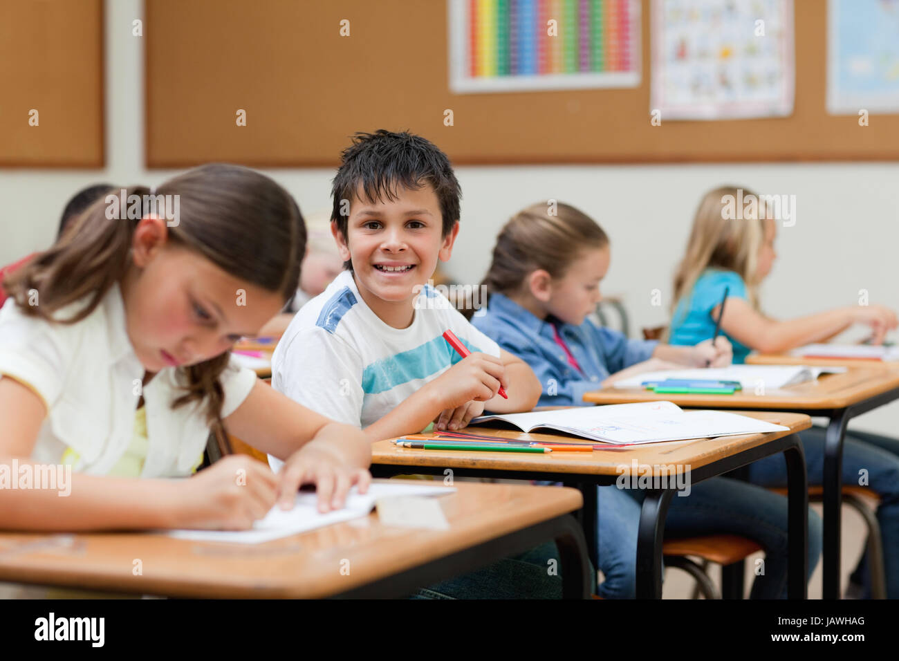 Side view of smiling student sitting at his desk Stock Photo - Alamy