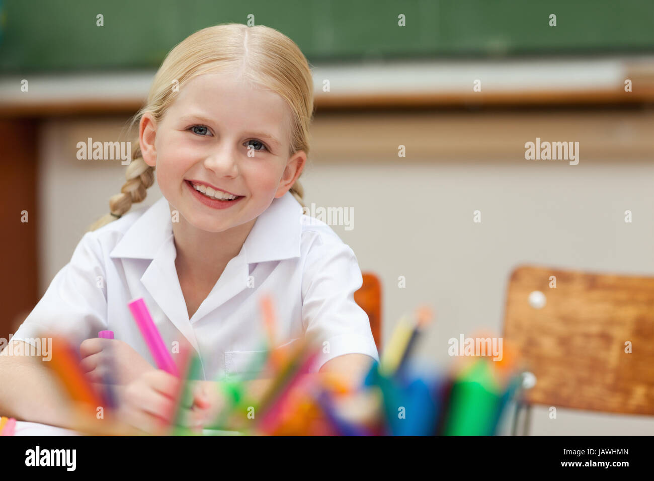 Smiling student sitting at desk with pen Stock Photo - Alamy