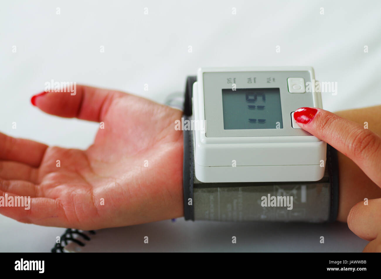 Close up of a young patient using an automatic tensiometer in her arm ...