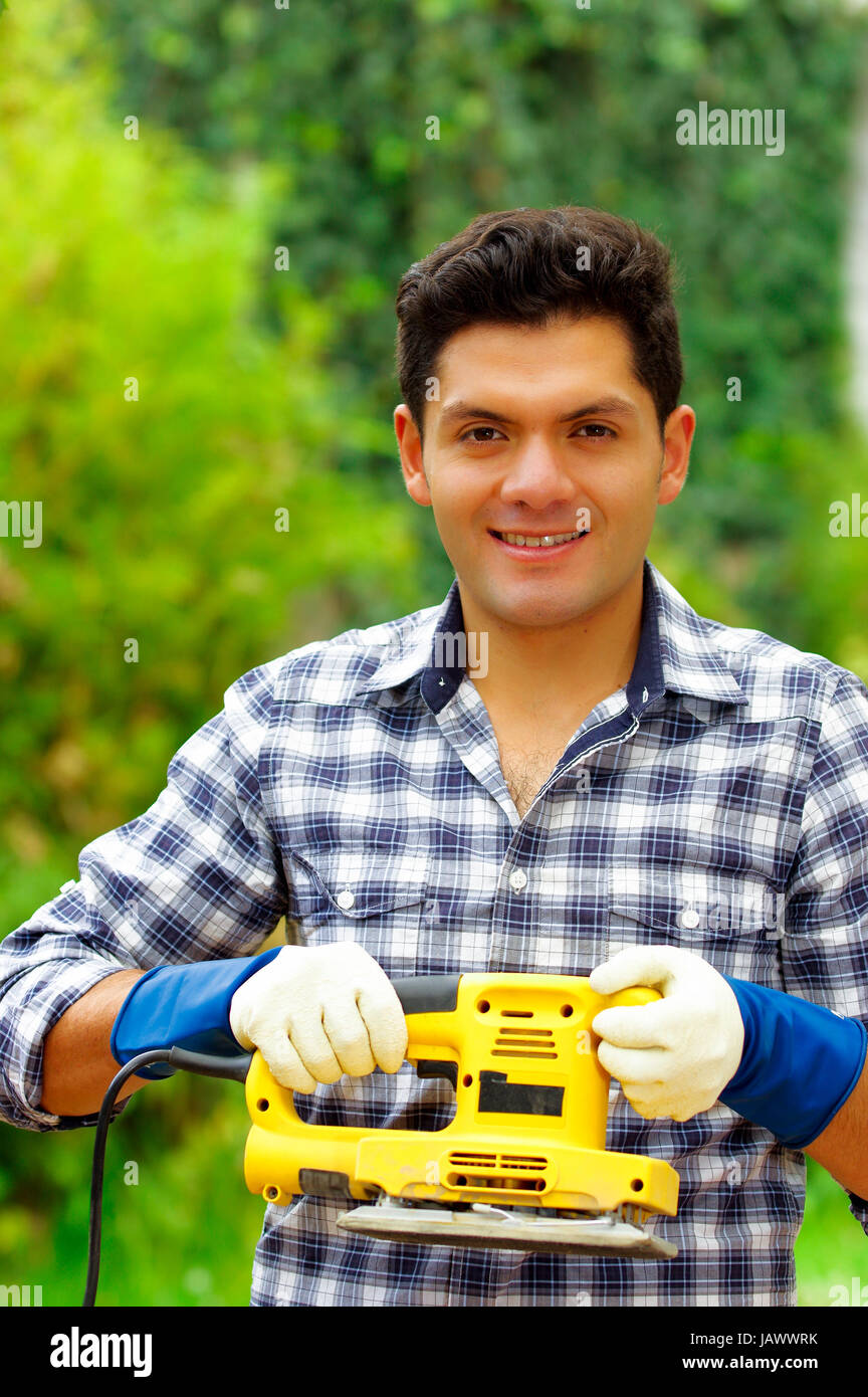 Close up of a man holding an electric sander on forest background Stock ...