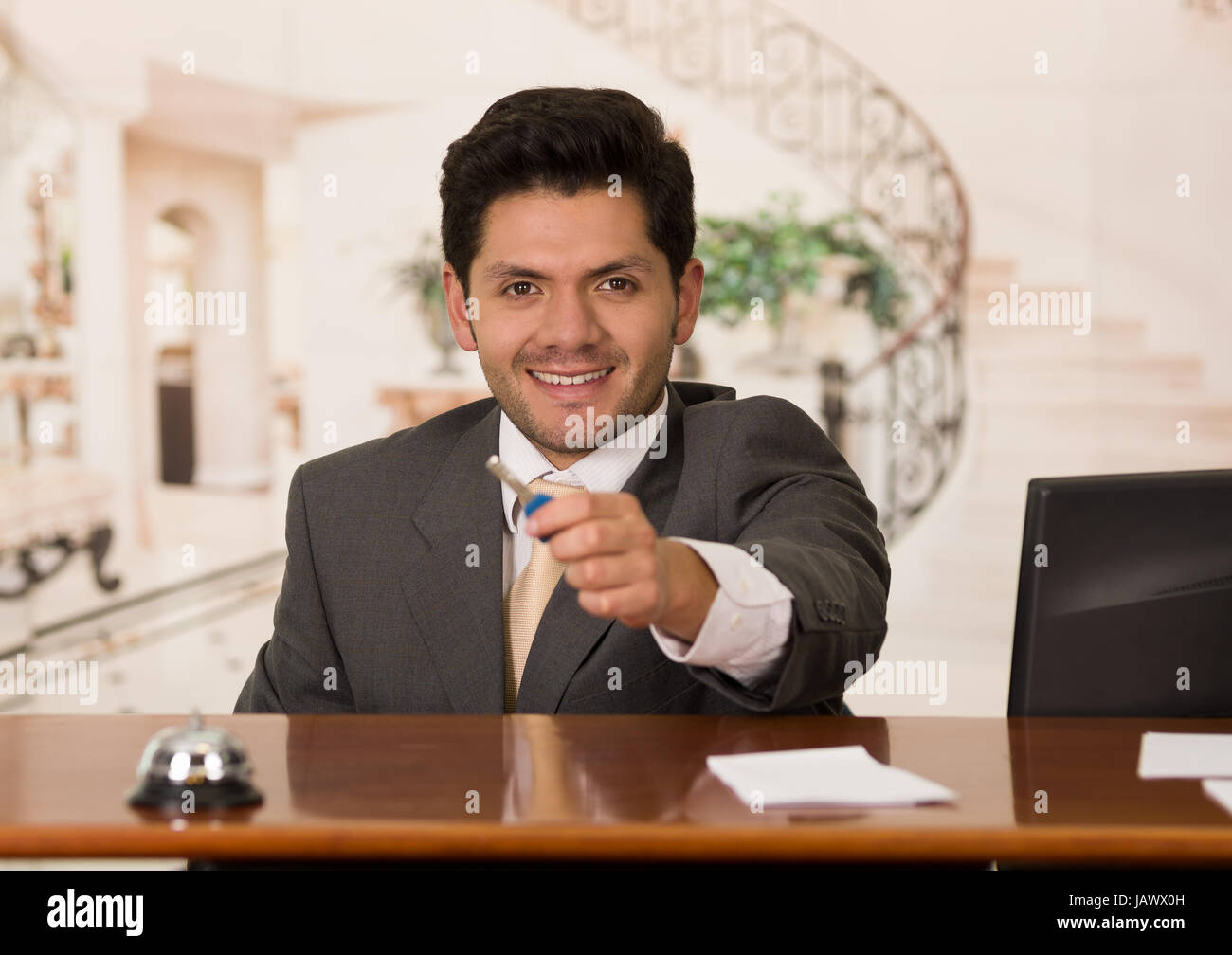 Happy smiling receptionist in hotel giving key to guest, hotel ...