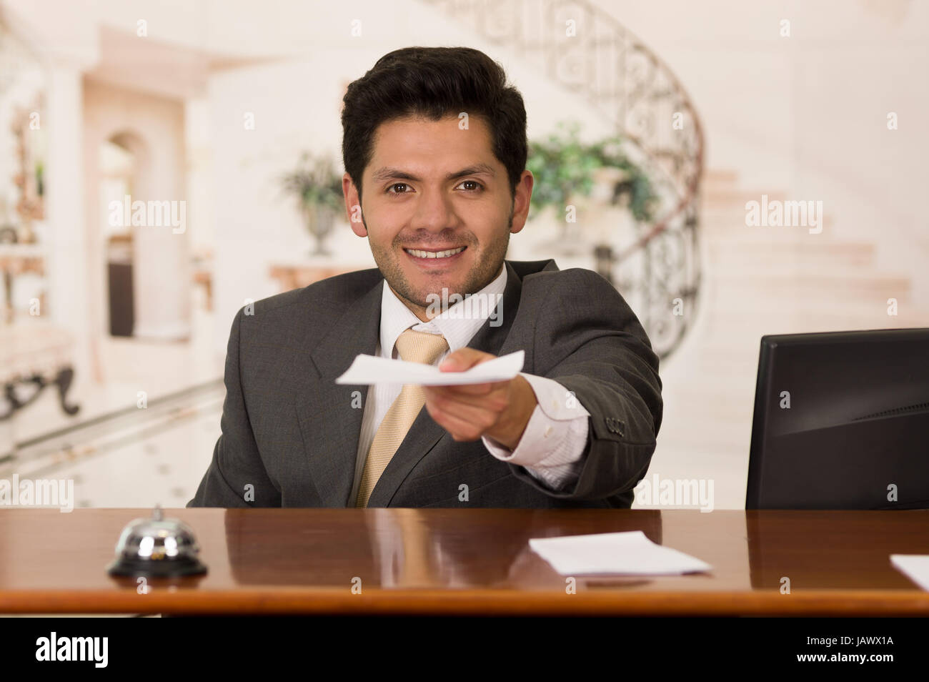 Happy smiling receptionist in hotel giving key to guest and papers to ...