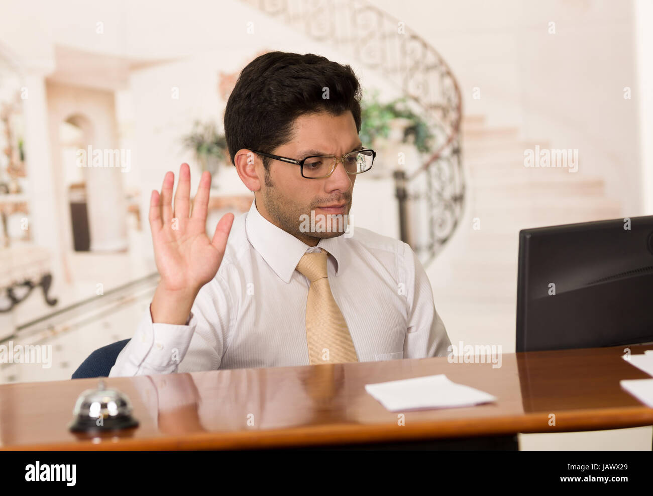 Serious receptionist in hotel wearing glasses and cheking in his ...