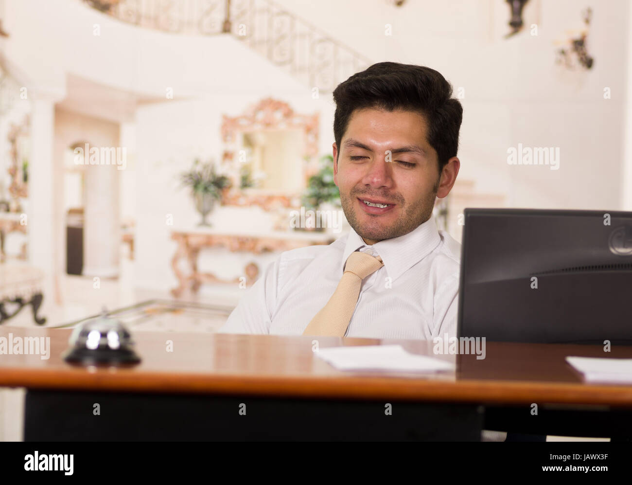 Sleepy young man receptionist in hotel working, in hotel background ...