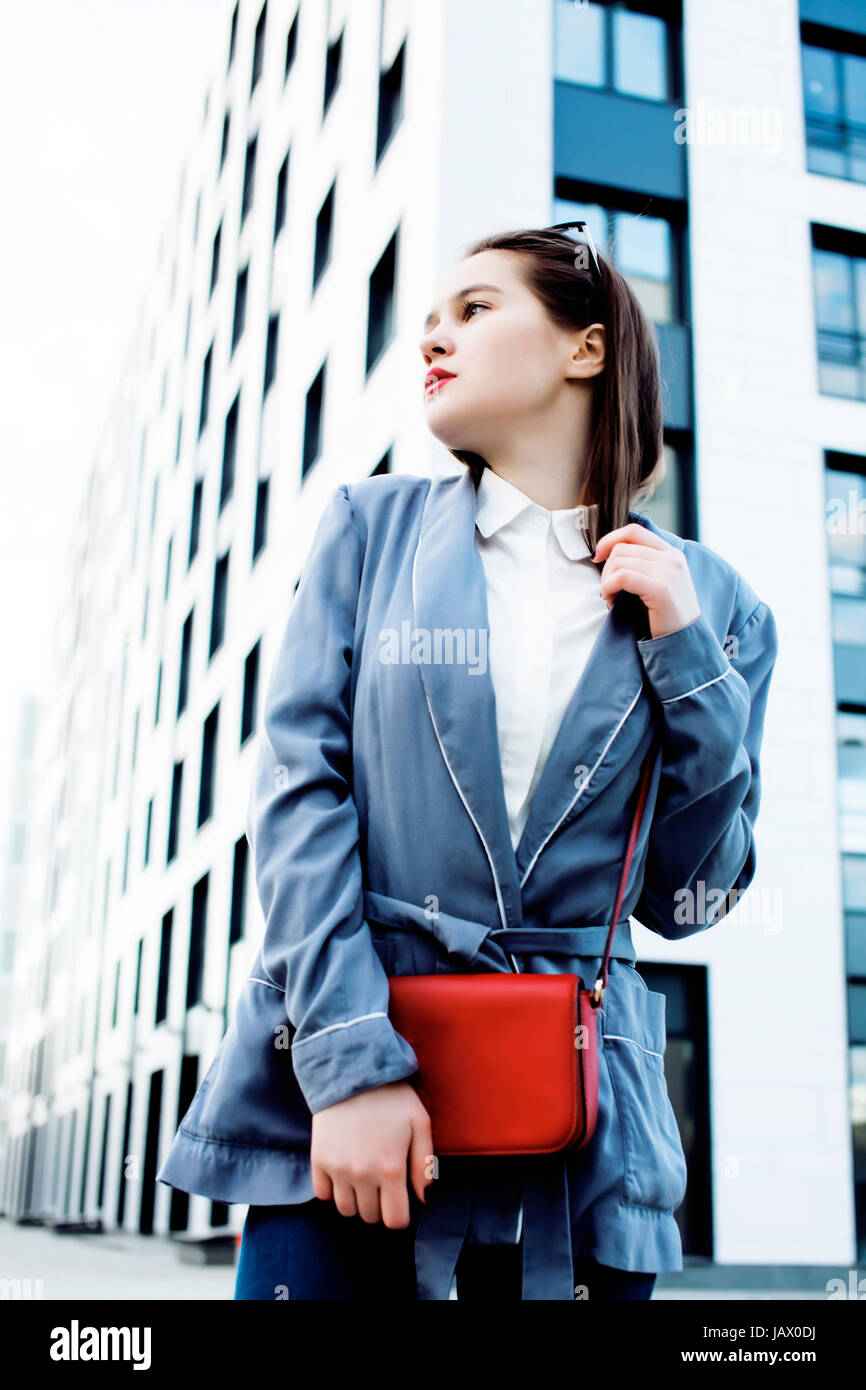 young pretty brunette business woman posing against modern building ...