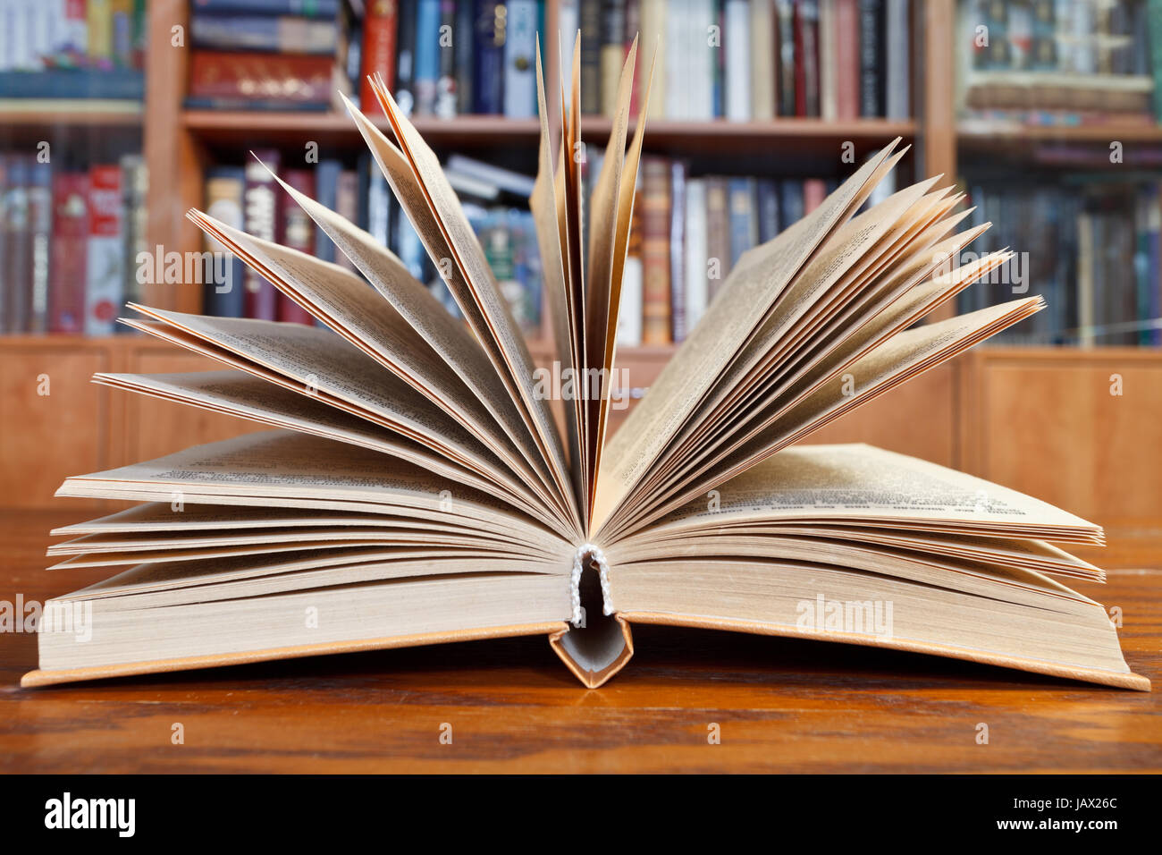fanned open book on wooden table near bookcases Stock Photo - Alamy