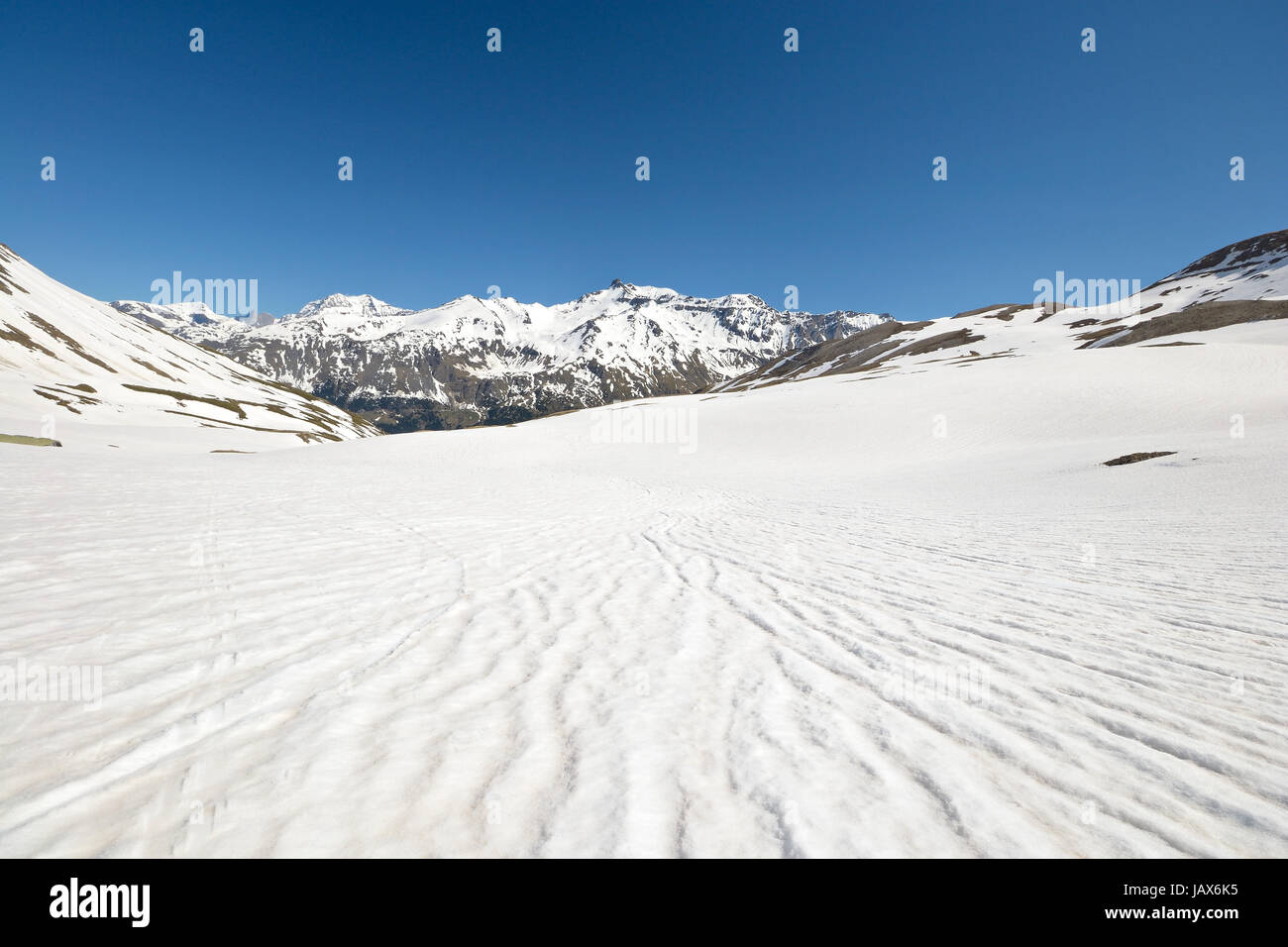 Snowy slope with melting grooves in scenic high mountain background and ...