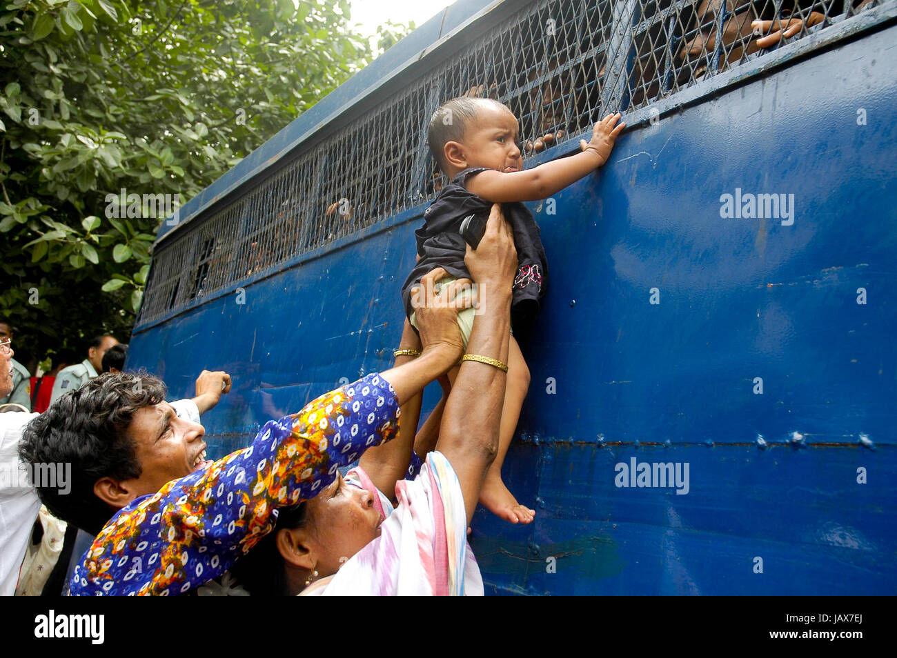 A prisoner fondles his baby from a prison van as his relative holds the ...