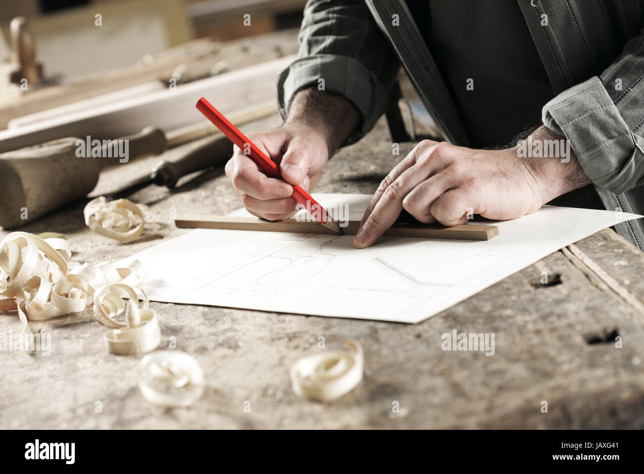 Closeup view of a carpenter using a red pencil to draw a line on a ...