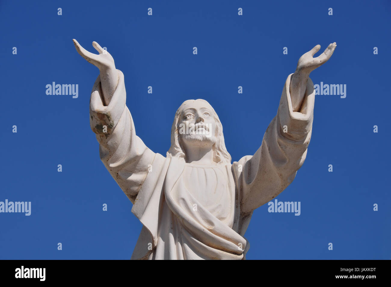 Jesus Christ with hands raised in blessing under blue sky. Marble ...