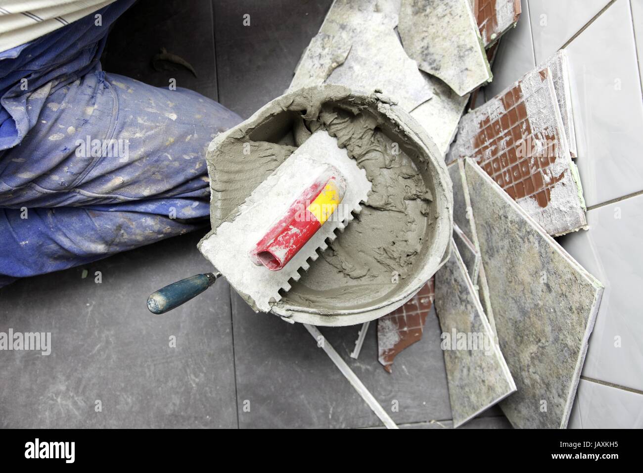 a tiler at work. bonding of floor tile with tile adhesive and filler ...