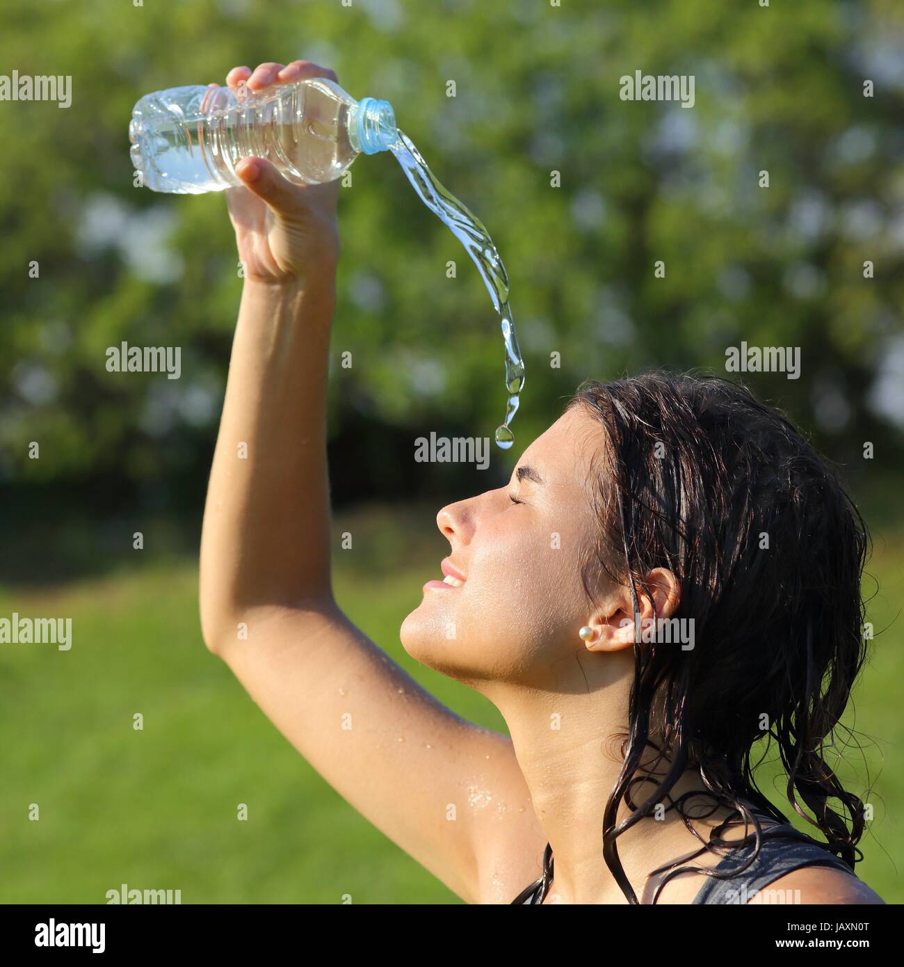 Beautiful woman throwing herself water from a plastic bottle with a ...