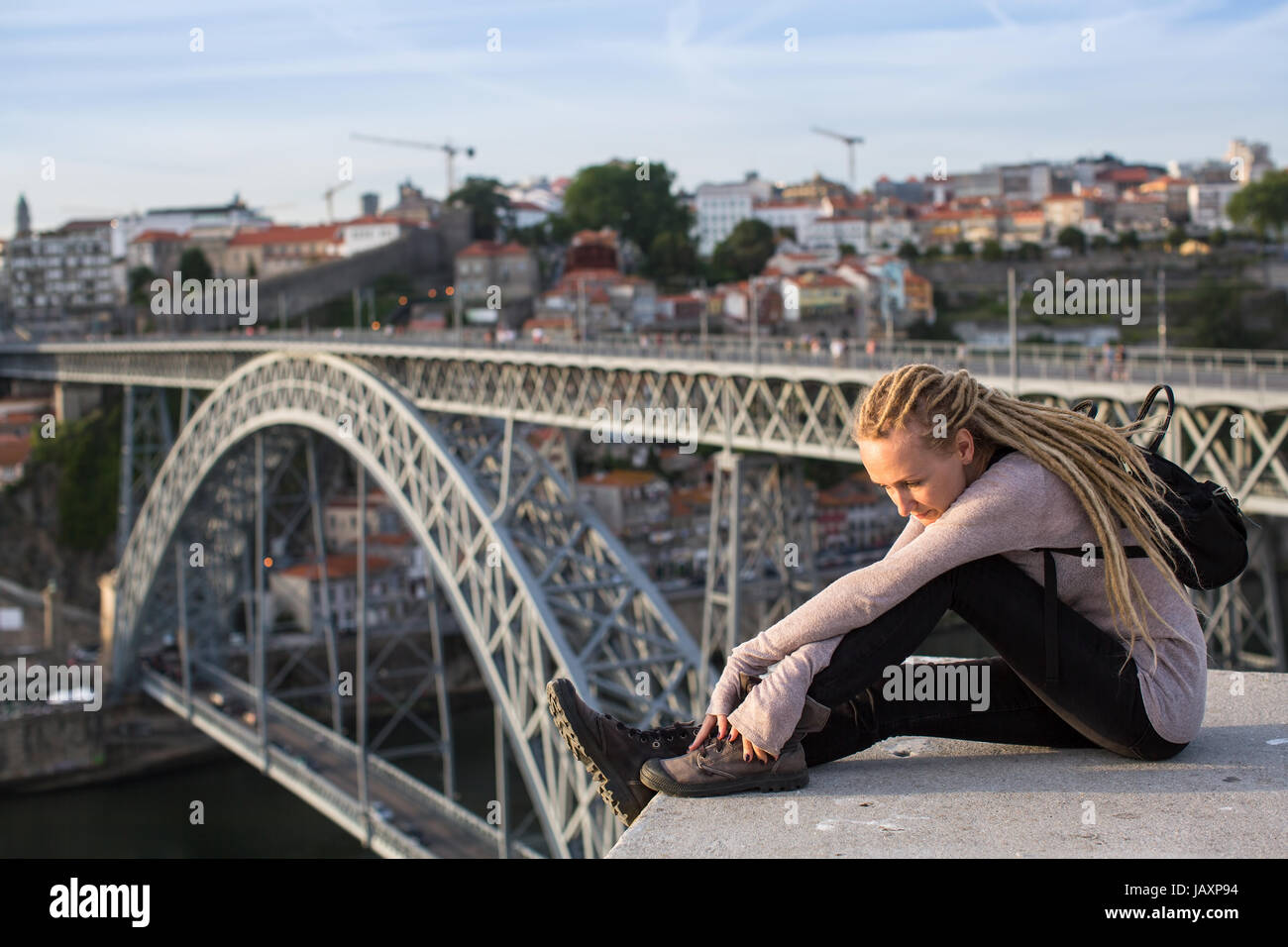 Young beautiful woman with dreadlocks sitting on the background of the ...