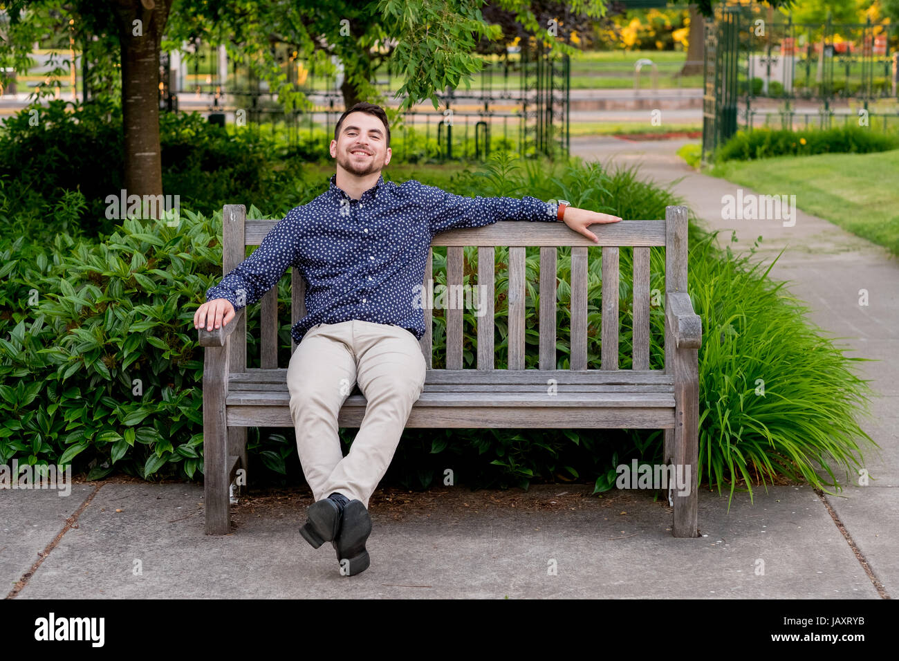 College grad student on a park bench on a beautiful university campus ...
