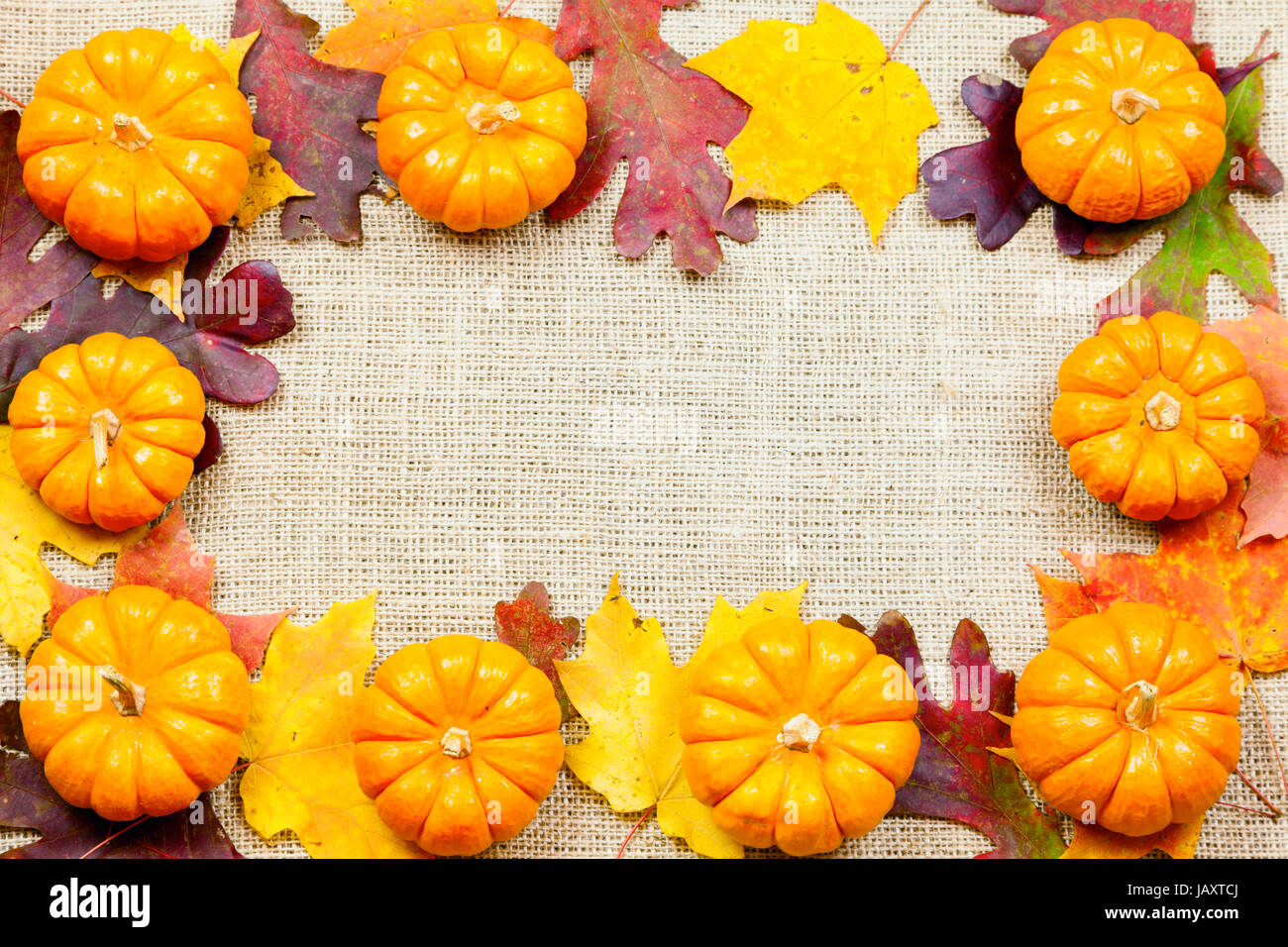 Fall-themed background of burlap, dry leaves and pumpkins Stock Photo ...